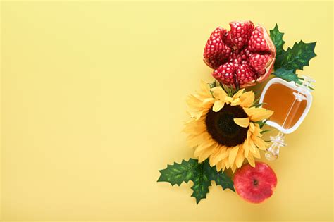 로쉬 하샤나 익은 석류 사과 꿀 해바라기 노란색 배경에 노란색 꽃 상징을 가진 작곡 유태인 Rosh Hashanah 휴일 속성 복사 공간이 있는 위쪽 보기입니다 0명에 대한