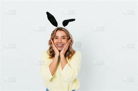 肖像快乐的年轻女子戴兔耳朵和黄色套头衫