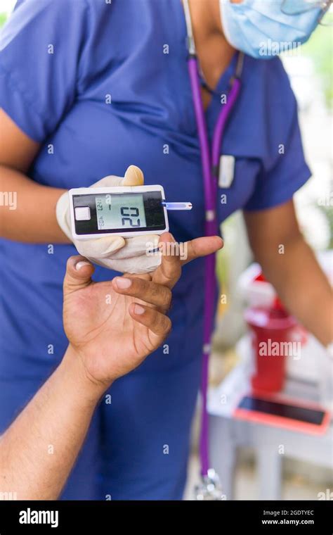 A Doctor Measuring Patients Blood Glucose With A Glucometer In A