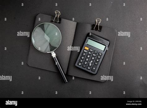 Top View Lupa And Calculator On Black Notepad Binder Clips On Dark