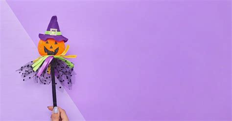 보라색 벽 위에 종이 마녀 모자를 들고 있는 손 사진 Unsplash의 할로윈 배경 이미지