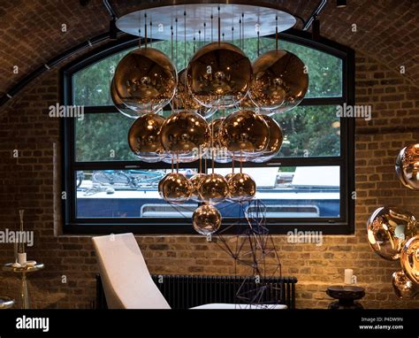 Cluster Of Tom Dixon Metallic Pendant Lights Hanging In Front Of A