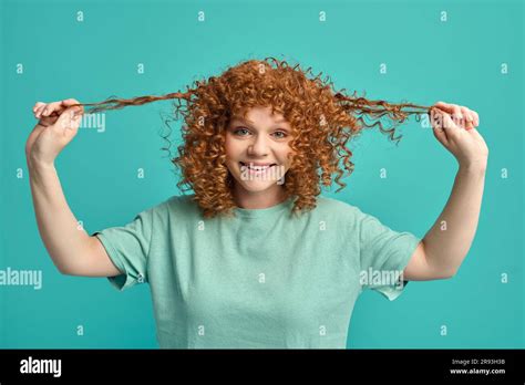 Portrait Of Attractive Happy Smiling Ginger Girl Pulling Her Curly Red