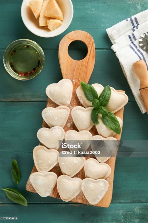 하트 모양의 이탈리안 라비올리 파스타 오래된 나무 파란색 배경에 밀가루와 바질을 곁들인 맛있는 생 라비올리 음식 조리 재료 배경입니다 발렌타인 데이 어머니의 날 점심