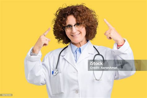 격리 된 배경 위에 중간 어른 수석 의사 여자 둘 다와 함께 머리를 가리키는 웃 고 손 손가락 좋은 아이디어 또는 생각 좋은 메모리 가리키기에 대한 스톡 사진 및 기타