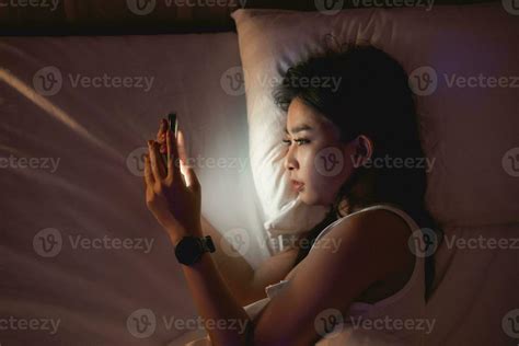 Asian Woman Using Mobile Phone Smartphone Laying On The Bed In The Bedroom Sleepy Exhausted