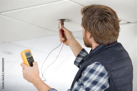 Electrician Using A Multimeter To Test Spotlight Connections Stock Photo Adobe Stock
