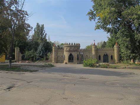 A Small Rustic Castle With Towers And A Gatehouse Stands In An Old Or Poorly Maintained Parking