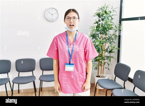 Young Asian Nurse Woman At Medical Waiting Room Angry And Mad Screaming