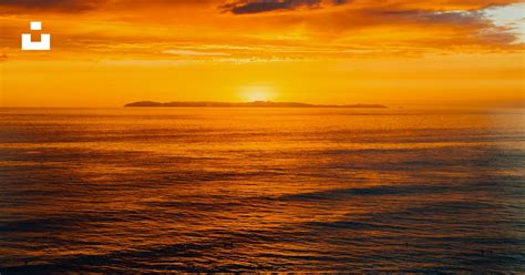 해질녘 바다 위의 주황색 하늘을 부분적으로 덮고 있는 녹색과 검은색 구름 사진 Unsplash의 무료 하늘 이미지