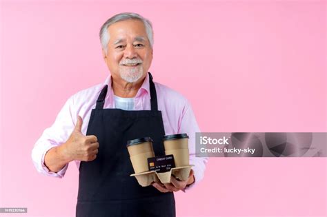 초상화 매력적인 은퇴 한 아시아 노인은 흰 콧수염과 앞치마를 입은 수염이 커피 종이 컵을 들고 있습니다 70 79세에 대한 스톡