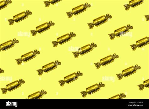 Pattern Made In Gold Wrapped Candy On Yellow Background Flat Lay Top