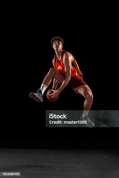 어두운 스튜디오 배경에 고립 된 농구 선수 훈련의 전체 길이 초상화 키가 큰 근육질 운동 선수가 공을 가지고 점프합니다 18 19세에 대한 스톡 사진 및 기타 이미지