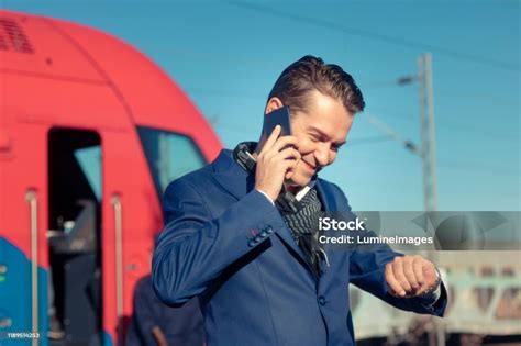 기차역에서 손목 시계에 시간을 확인 하면서 전화에 얘기 하는 행복 한 남자 시간 확인에 대한 스톡 사진 및 기타 이미지 시간 확인 지하철 승강장 철도 승강장 Istock