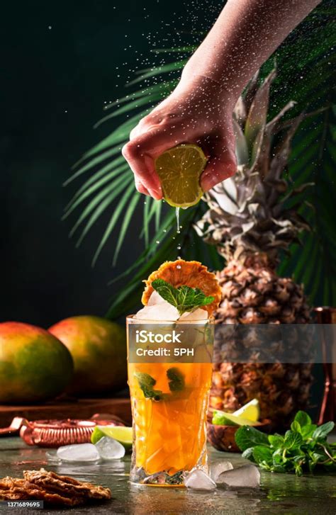 보드카 파인애플 주스 망고 얼음여름 칵테일 긴 음료 또는 차가운 목테일 바텐더 손은 라임 주스 냉동 움직임 및 비행 방울을 짜냅니다 야자수 잎을 가진 열대 배경 마르가리타에