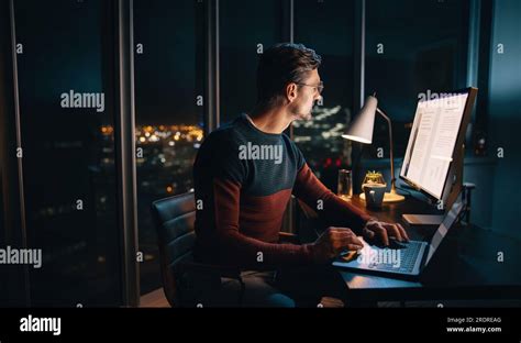A Focused Businessman Works Late In A Well Lit Office Typing On His