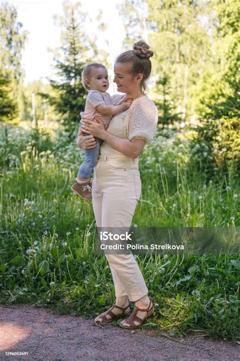 한 젊은 어머니가 한 살 짜리 아기와 함께 걷고 그를 품에 안고 안고 있다 그의 조화로운 발전을위한 아이와의 의사 소통 12