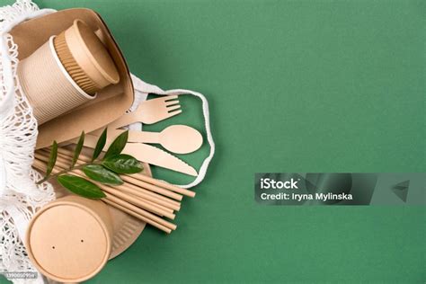 Kraft 종이 음식 컵 접시 및 용기는 복사 공간이있는 녹색 배경에 흰색 면봉지에 담겨 있습니다 길거리 음식은 종이기구를 제거합니다 컵 접시 마시는 빨대 나무 칼 붙이 0