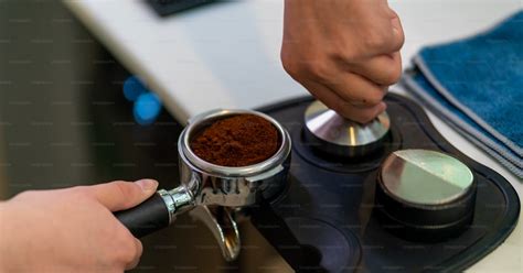 아시아 남자 커피 숍 파트 타임 직원은 커피 머신에서 뜨거운 커피를 양조합니다 커피 메이커에서 분쇄 커피로 에스프레소를 만드는 남성 바리스타 중소 기업 소유자와