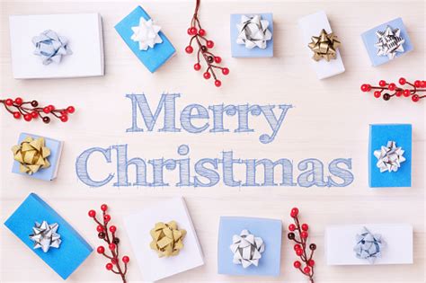 가벼운 나무 배경 비문 메리 크리스마스의 센터 주위에 흰색과 파란색 선물 상자 리본 빨간 장식 장과 함께 축제 사진입니다 계절에