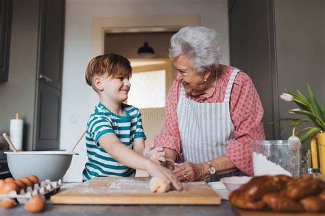 Grandmother With Grandson Preparing Traditional Easter Meals Kneading Dough For Easter Cross
