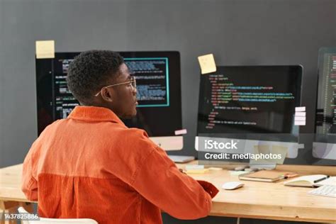 Rear View Of Young Black Man Concentrating On Decoding Data On Computer