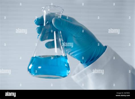 A Dedicated Scientist Holds An Erlenmeyer Flask With Vibrant Blue