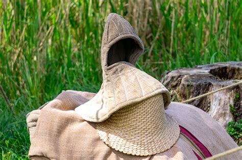 리넨 후드와 밀짚모자와 같은 역사적인 의류 아이템이 키 큰 풀과 나무 그루터기를 배경으로 자연 환경에서 천 가방에 놓여 있는 클로즈업 0명에 대한 스톡 사진 및 기타 이미지