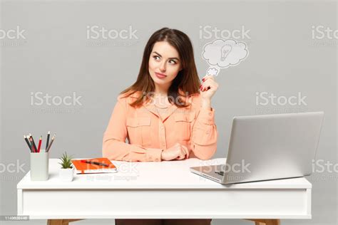 파스텔 옷을 들고 있는 젊은 충격 여자 전구 구름 말 회색 배경에 고립 된 Pc 노트북 책상에서 작업 앉아 성취 비즈니스 커리어 라이프 스타일 컨셉 복사 공간을 모의 합니다