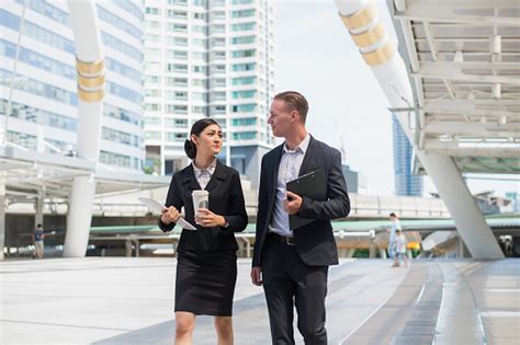 문서 파일 및 플라스틱 찻잔을 손에 들고 아시아 비즈니스 여자에 대해 얘기 비즈니스 미래 백인 사업가 그들은 함께 도시에서 도보