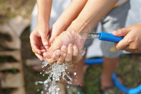 Una Madre Usa Agua Para Lavar Las Manos De Su Hijo Foto Premium