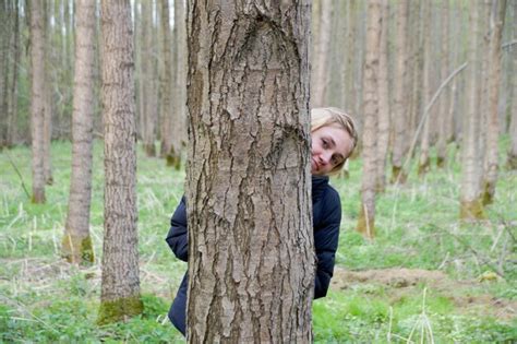Premium Photo Portrait Of Woman Hiding Behind Tree At Forest