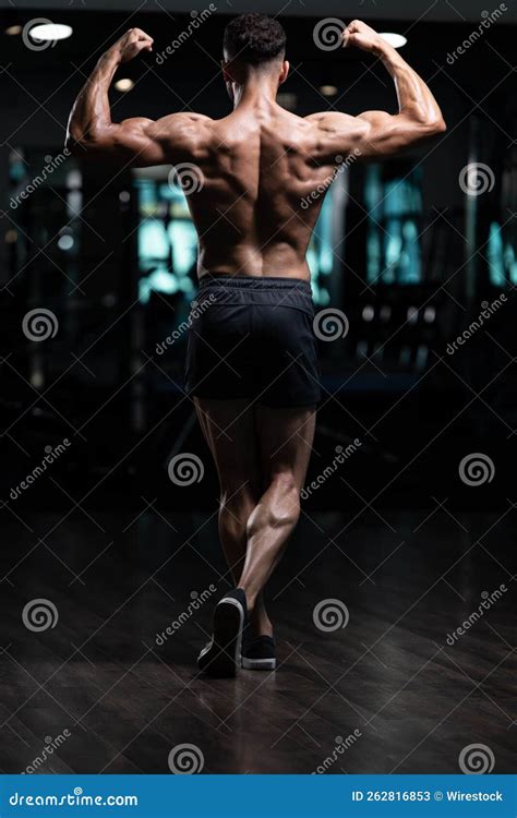 Handsome Young Man Standing Strong And Flexing Muscles In Gym Stock