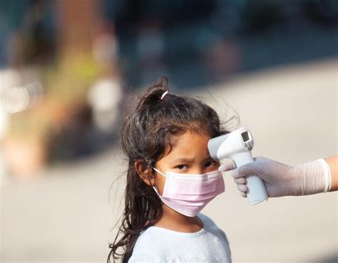 Premium Photo Cropped Hand Checking Temperature Of Cute Girl Outdoors