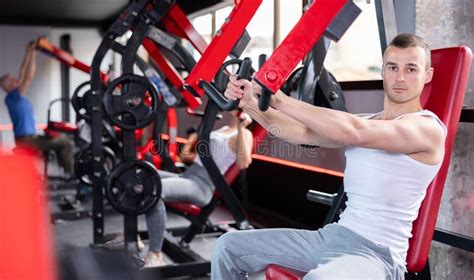 Portrait Of Man Doing Triceps Curls In Exercise Machine During Strength Training In Gym Stock