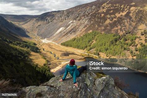 글렌달로 위클로 산맥의 호수와 풍경에 감탄하는 산 꼭대기의 바위에 앉아있는 여성 하이커 하이킹에 대한 스톡 사진 및 기타 이미지
