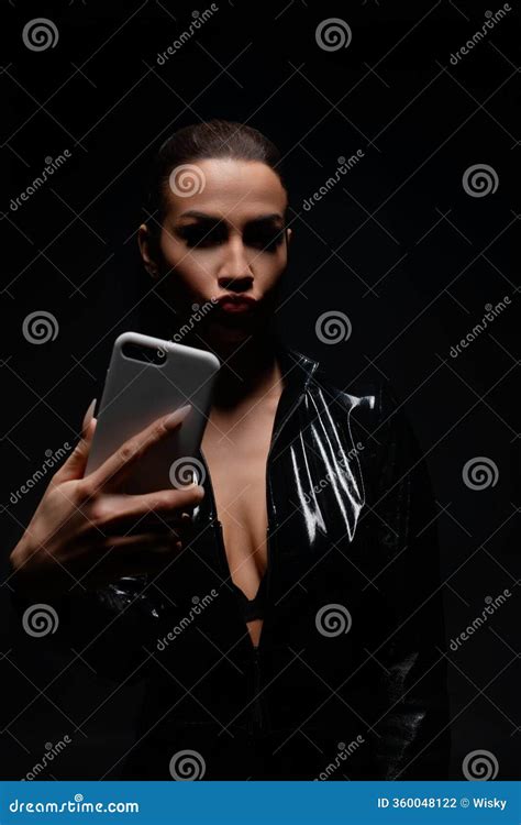 Woman In Sleek Attire Taking A Selfie In An Intimate Dark Setting Stock