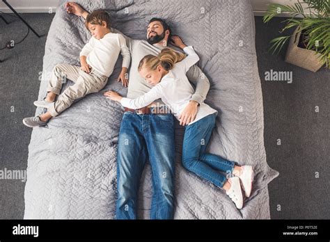 Overhead View Of Father And Siblings Sleeping On Bed Together Stock
