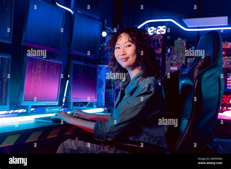 Female Asian Hacker Smiling In Hideout Place With Dark Environment And