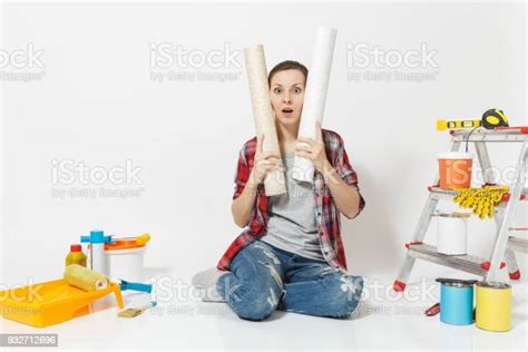 벽지와 바닥에 앉아 캐주얼 옷에서 여자 롤 흰색 배경에 고립 된 재건축 아파트에 대 한 악기 페인팅 도구를 붙이기 위한 액세서리입니다 수리 가정 개념입니다 공간 복사 개선에