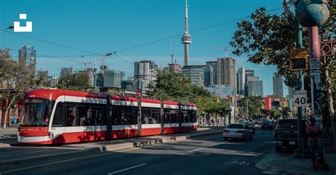 배경에 자동차와 건물이 있는 거리에 있는 빨간색과 흰색 트롤리 사진 Unsplash의 무료 토론토 이미지