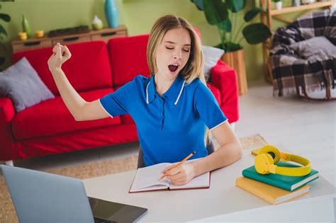 좋은 금발의 십대 소녀 하품 스트레칭 피곤한 졸린 Elearning 원격 학습 착용 푸른 옷 즐길 수 있는 현대적인 인테리어 평면 실내의 사진 16 17 살에 대한 스톡