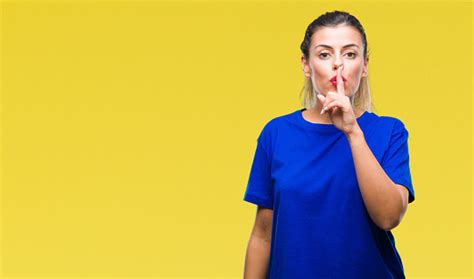 입술에 손가락으로 조용히 하 라는 고립 된 배경 위에 캐주얼 블루 티셔츠를 입고 젊은 아름 다운 여자 침묵 그리고 비밀 개념입니다 T 셔츠에 대한 스톡 사진 및 기타 이미지