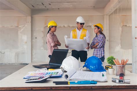 팀워크 웨어 안전복 트러스트 팀과 함께 건설 현장에서 토목 건설 엔지니어 팀 미팅에서 안전 하드 햇 건설 엔지니어 컨셉을 함께 테이블 컨설팅에 파란색 프린트를 살펴봅니다
