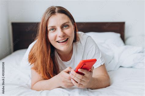 Foto Stock Beautiful Babe Woman Reading Text Message On Her Mobile Phone In The Bed Check