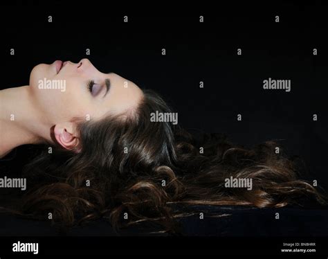 Young Beautiful Woman On Black Background With Hair Laid On Ground With