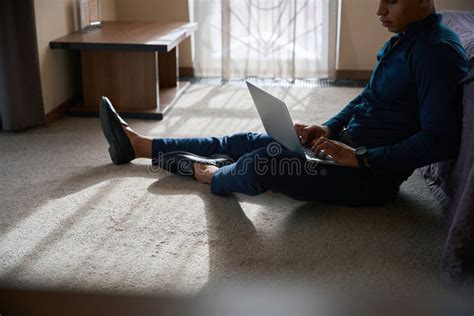 Obscure Face Side View Of African American Businessman Typing On Laptop On Floor Stock Image