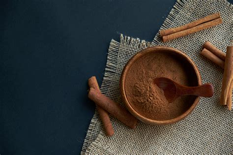 계피 스틱 소박한 스타일에 황마 밧줄로 묶여 나무 그릇과 빈티지 스쿱에 계피를 갈아 줍니다 검은 색 배경을 닫습니다 텍스트공간을 복사합니다 상단 보기 플랫 레이 가루로