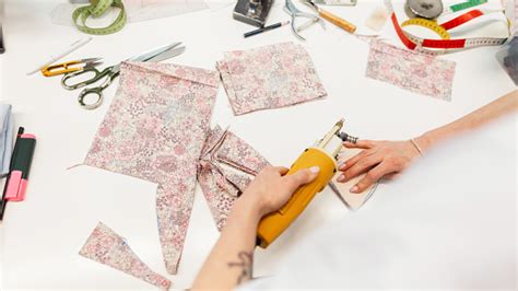 일렉트로 샤프가 있는 테일러 재봉사가 스튜디오의 데스크탑에서 천을 자릅니다 센티미터 천 가위 및 기타 재봉 도구가 있는 작업장