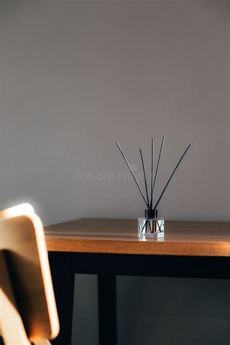Aroma Diffuser In A Clear Glass Bottle With Black Cap On Wooden Table On A Strip Of Sunlight